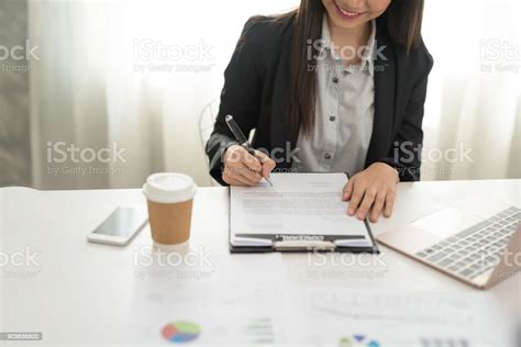 그녀의 워크스테이션에 계약 종이 서명 하는 직장에서 사업가 계약서에 대한 스톡 사진 및 기타 이미지 계약서 교섭 금융