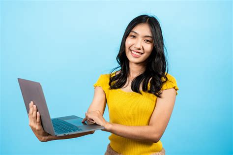 초상화 셔츠 노란색 스타킹을 입은 긴 머리 소녀 손에 노트북 컴퓨터를 들고 다른 손은 키보드를 누르는 데 사용 친구와 채팅을 입력하는 데 사용 파란색 배경에 고립된 실내