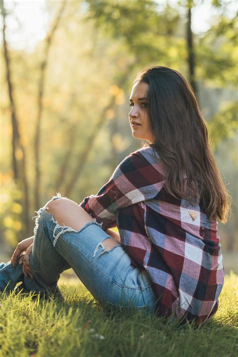 빨간색 흰색과 파란색 격자 무늬 셔츠와 파란색 데님 청바지를 입은 여자가 땅에 앉아 있다 사진 Unsplash의 무료 의복 이미지