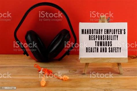 건강 및 안전 개념 건강과 안전에 대한 Mandotary 고용주의 저장소와 빨간색 배경 위에 나무 테이블에 개인 보호 장비 0에