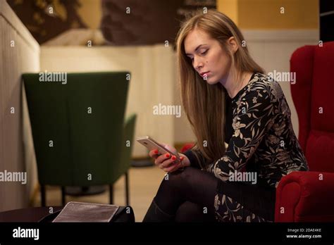 Young Woman With Long Hair Sitting In A Red Chair And Talking On The