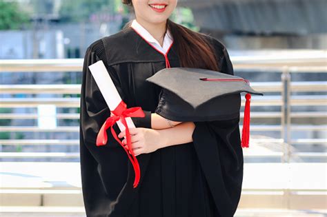 행복한 미소 졸업 학생 광장 학술 모자 모자와 인증서를 들고 젊은 아름다운 아시아 여성 마천루 건물 배경으로 도시에 교차 팔을