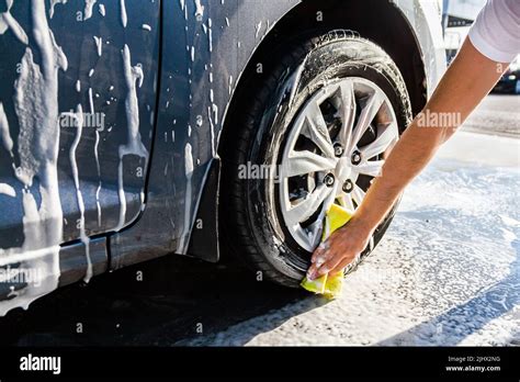 A Man Washes His Car With Foam At A Self Service Car Wash Wheels And