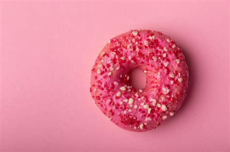 분홍색 배경에 도넛 분홍색 아이싱이 있는 딸기 도넛과 종이 배경에 뿌린다 화려한 미니멀리즘 개념 정크 푸드 Sweets복사 공간