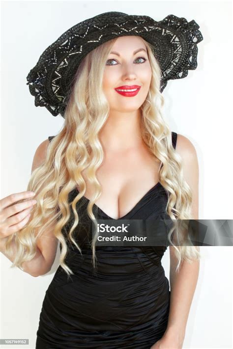Beautiful Young Woman Blonde In Black Dress And Hat With Decollete