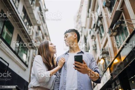 젊은 아시아 커플 도시 거리를 따라 걷고 채팅 하 고 스마트폰을 사용 하는 동안 웃 고 2명에 대한 스톡 사진 및 기타 이미지