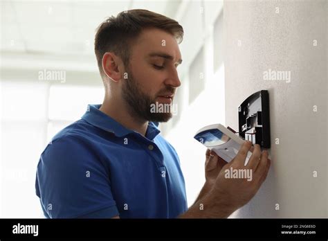Man Installing Home Security System On White Wall In Room Stock Photo Alamy