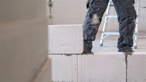 The Builder Places The Block During The Construction Of The Wall Stock