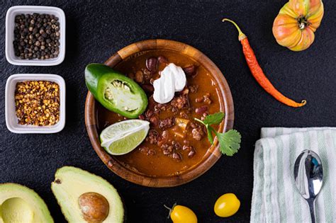 검은 배경에 고수 라임 할라피뇨 고추로 장식된 칠리의 나무 그릇 아보카도 노란 방울 토마토 마른 핫 칠리 페퍼 건강한 식생활에 대한 스톡 사진 및 기타 이미지 Istock