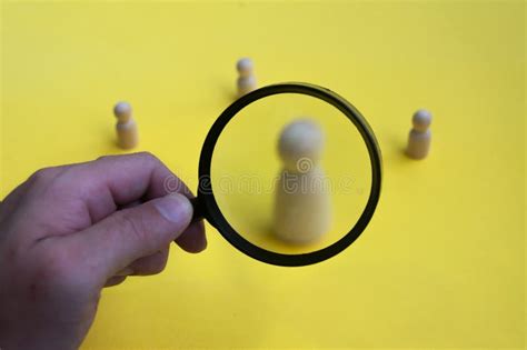 Hand Holding Magnifying Glass Focusing On Wooden Figure Employment
