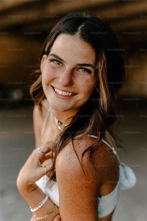 하얀 탱크탑을 입은 여자가 카메라를 보며 웃고 있다 사진 Unsplash의 몰래 이미지