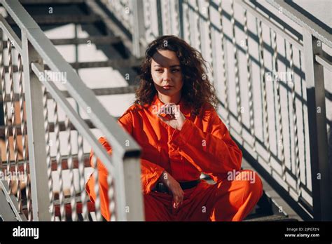 Young Brunette Curly Woman In Orange Suit Female In Colorful Overalls