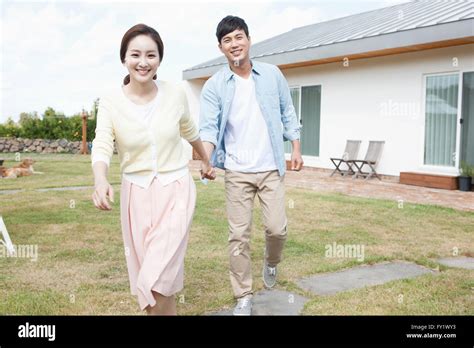 Couple Running Hand In Hand At The Yard Of A House Representing Rural