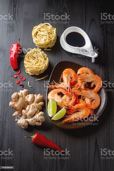아시아 문화입니다 신선한 생 새우 국수 고추 생강 나무 테이블에 그릇에 간장 해산물을 먹고 어두운 배경입니다 상위 뷰 갑각류에