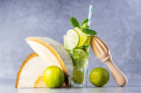 라임 신선한 민트와 얼음유리로 모히토 여름 칵테일 모히토 회색 배경에 나무조각과 수동 주스기 크리에이티브 컴포지션 각얼음에 대한