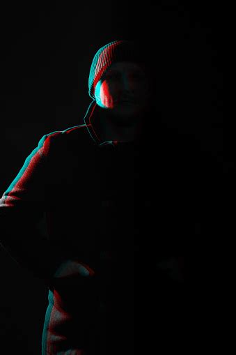 그림자와 실루엣에 숨어있는 코트와 모자를 쓴 남자는 글리치와 Rgb 색상 분할 효과 스타일의 빛으로 빛납니다 분리에 대한 스톡