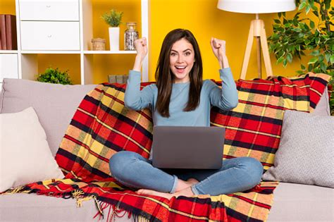 매력적인 기뻐하는 아가씨의 전체 길이 사진은 주먹을 들어 올리고 소파에 앉아 맨발로 노란색 배경에 고립되어 있습니다 20 24세에 대한 스톡 사진 및 기타 이미지 Istock