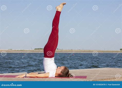 Young Girl Practices Yoga On The Shore Of The Lake The Concept Of