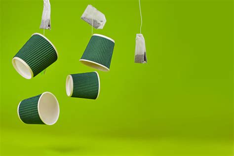 일회용 골판지 컵과 티백이 공중에서 날아오다 녹색 배경에 종이 컵 안경 근처에 텍스트를 위한 공간과 여유 공간을 복사합니다