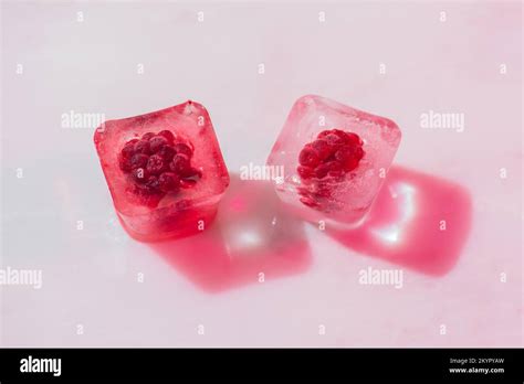 Frozen Raspberry In Ice Cube Close Up In White Marble Surface Stock