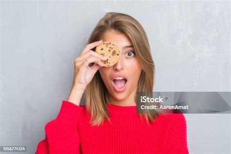 그런 지 회색 벽 먹는 초콜릿에 아름 다운 젊은 여 자가 칩 과자 깜짝 얼굴 두려워 하 고 공포 식으로 흥분 충격에서 무서 워 눈 신체 부분에 대한 스톡 사진 및 기타