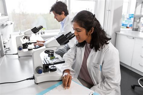 Scientists With Microscopes Working In Laboratory Resource Center For