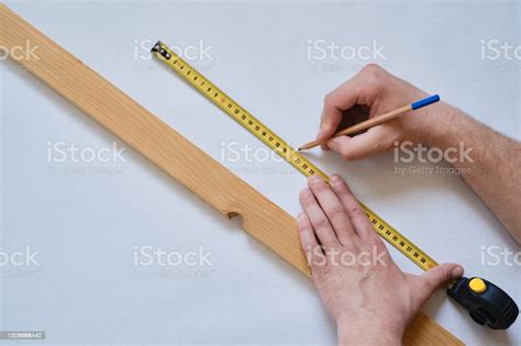 한 남자가 테이프 측정으로 나무 조각을 측정합니다 작업자가 수리합니다 빌더 수리공은 연필 자국을 만든다 건설리노베이션 공사