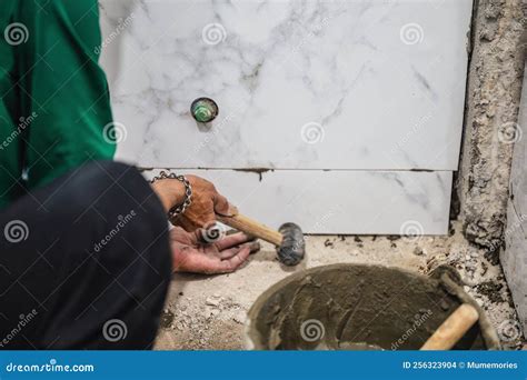 A Male Tiler Manually Glues Ceramic Tiles To The Bathroom Wall