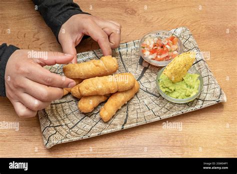Chefs Hands Placing Portion Of Fried Venezuelan Tequeños On A Log