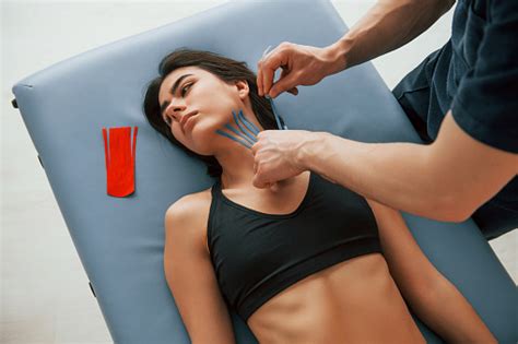 테이블 위에 누워 피부에 키네시오 테이프를 붙이는 생리학자를 방문하는 여성 25 29세에 대한 스톡 사진 및 기타 이미지