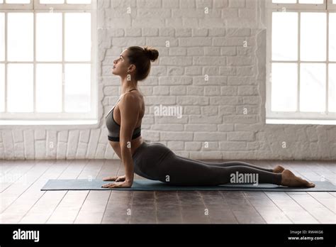 Young Woman Practicing Yoga Lying In Cobra Pose Bhujangasana Stock