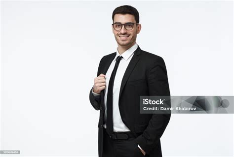 잘생긴 백인 남자의 길이 세로 입고 검은 양복 흰 셔츠와 넥타이 조용히 유리를 통해 찾고 긍정적으로 그리고 자신 있게 웃 고 회색 배경에 고립 30 39세에 대한 스톡 사진