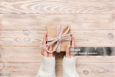 여자 손에 핑크 리본 종이에 포장된 발렌타인 또는 다른 휴일 수 제 선물을 제공합니다 선물 상자 흰색 나무 테이블 복사 공간