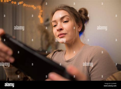 A Pretty Girl Is Looking Attentively At The Display Of A Portable Game