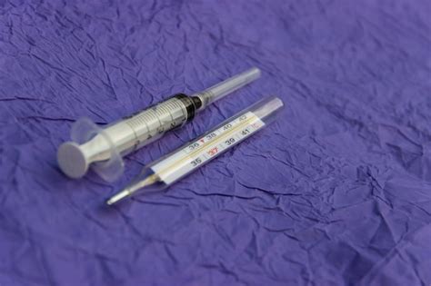 Premium Photo A Medical Syringe And A Thermometer For Measuring Body