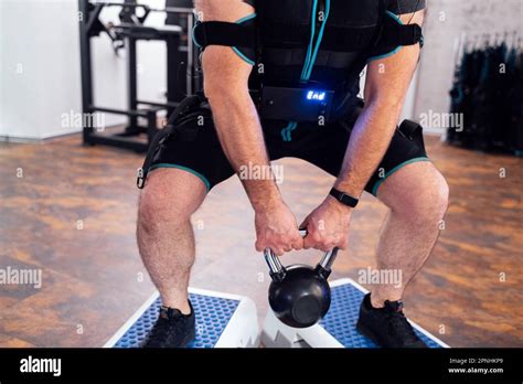 Strained Man In Ems Suit Standing On Step Platforms And Doing Squats
