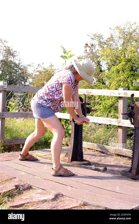 Woman Operating Canal Lock Using A Windlass Tool To Move Lock Gate