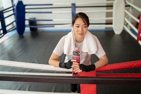 여자 파이터 걸 파워 권투를 감싼 여자 파이터는 권투 링에 서서 보호 붕대를 감고 밧줄에 기대어 휴식을 취합니다 강한 강력한 소녀 근력 운동 운동에 적합합니다 권투 스포츠에