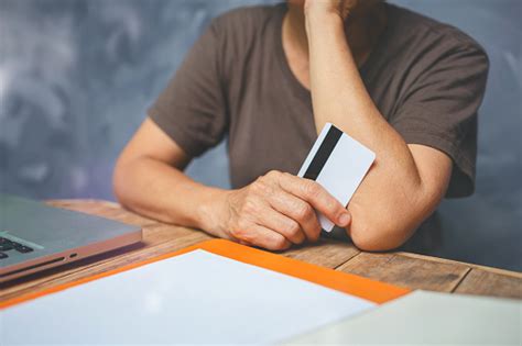 고위 여자 회색 콘크리트 배경 가진 오래 된 나무로 되는 테이블에 그녀의 신용 카드를 보여줍니다 고객에 대한 스톡 사진 및 기타