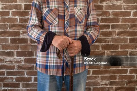 벽돌 배경에 격리된 겨울 체크무늬 셔츠를 입고 서 있는 힙스터 노인의 부분적으로 보기 그의 손에 지팡이 70 79세에 대한 스톡