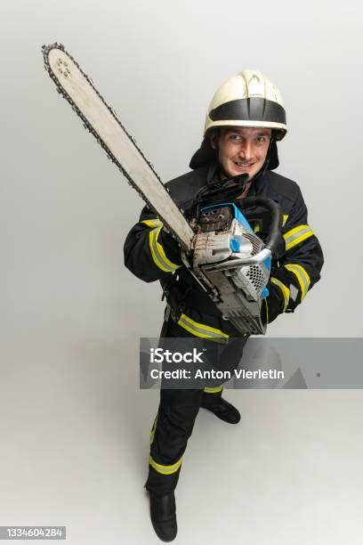 흰색 스튜디오 배경에서 톱으로 포즈를 취한 제복을 입은 미소 짓는 남성 소방관 25 29세에 대한 스톡 사진 및 기타 이미지 25 29세 겨냥 광고 Istock