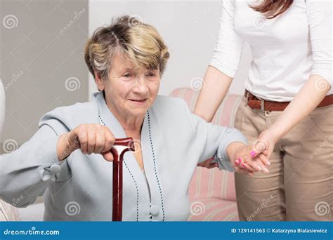 Caregiver Supporting Senior Woman With Walking Stick Stock Image