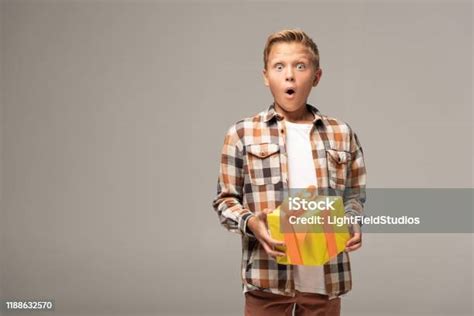 노란색 선물 상자를 들고 회색에 고립 된 카메라를보고 충격 소년 귀여운에 대한 스톡 사진 및 기타 이미지 귀여운 남성 노랑 Istock