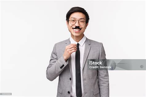 회색 정장에 재미 있고 바보 잘 생긴 아시아 남성의 허리 업 초상화 콧수염과 미소와 막대기를 들고 사무실 파티에 참석 동료와