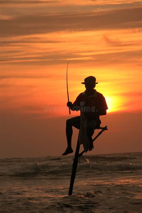 Silueta De Un Pescador Que Lanza Una Red En Un Lago Foto De Archivo
