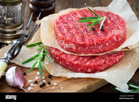 Raw Mince Meat Beef Burgers On A Wooden Cutting Board With Fresh