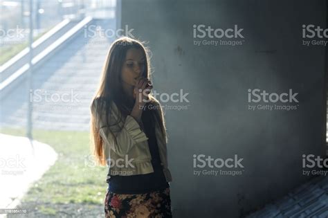 Vape 십대 캐주얼 한 옷을 입은 어린 귀여운 소녀가 여름날에 야외에서 전자 담배를 피울 수 있습니다 나쁜 습관 십대에 대한