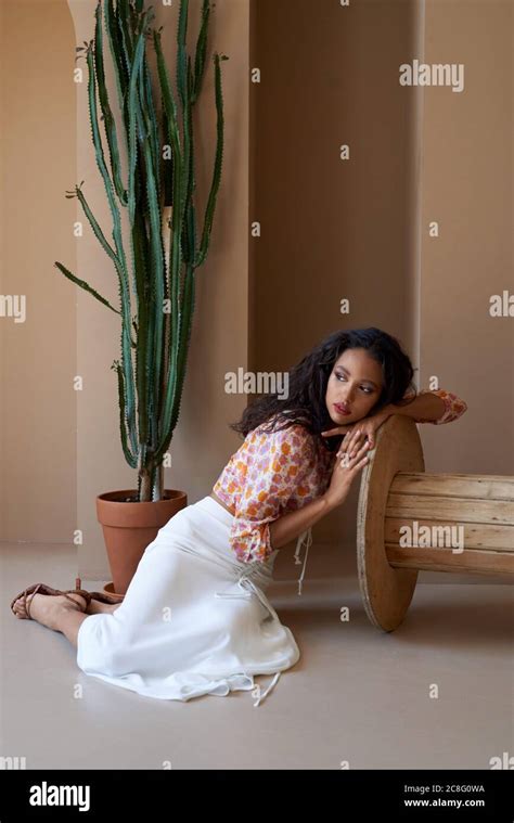 Gorgeous Mulatto Girl With Curly Hair Posing Near Tall Succulent Plant