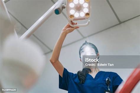 돋보기를 가진 아시아 중국 여성 치과 의사 환자에서 위에서보고있는 외과 적 빛을 조정하십시오 간호사에 대한 스톡 사진 및 기타