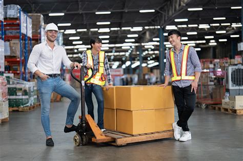 대형 창고 창고에서 일하는 관리자와 직원은 상자 옆의 손 팔레트 트럭 스택 근처에서 행복한 미소 짓는 초상화 사진을 서 있습니다 3 명에 대한 스톡 사진 및 기타 이미지